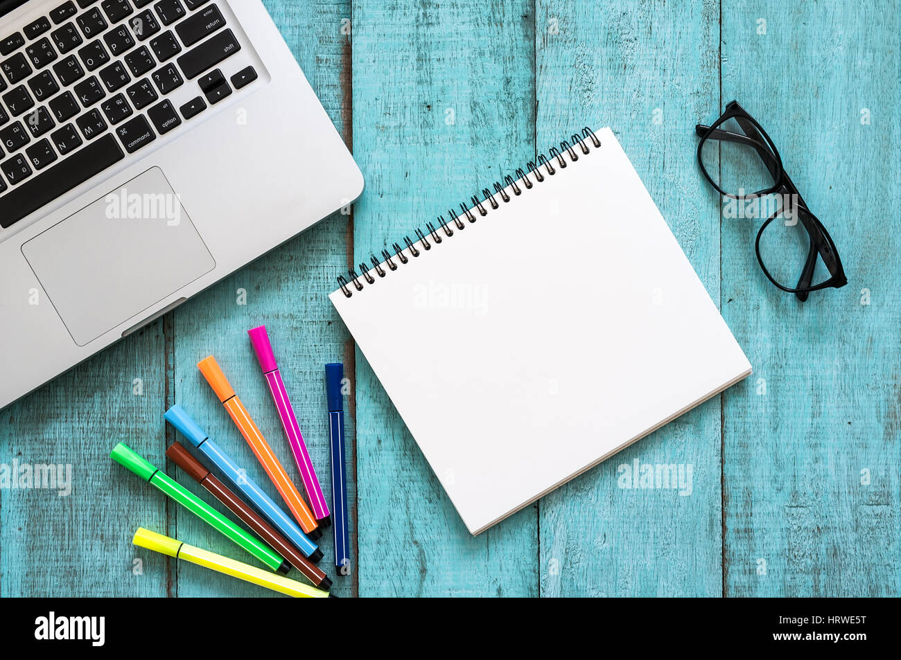 Blue wooden desk table with notebook, computer laptop, color pen and ...