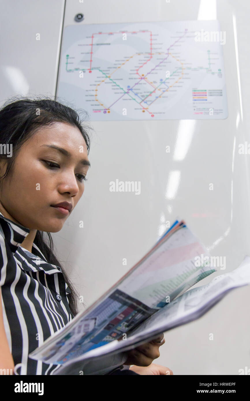 Asian tourist looks at the maps in the subway. A woman reading urban ...