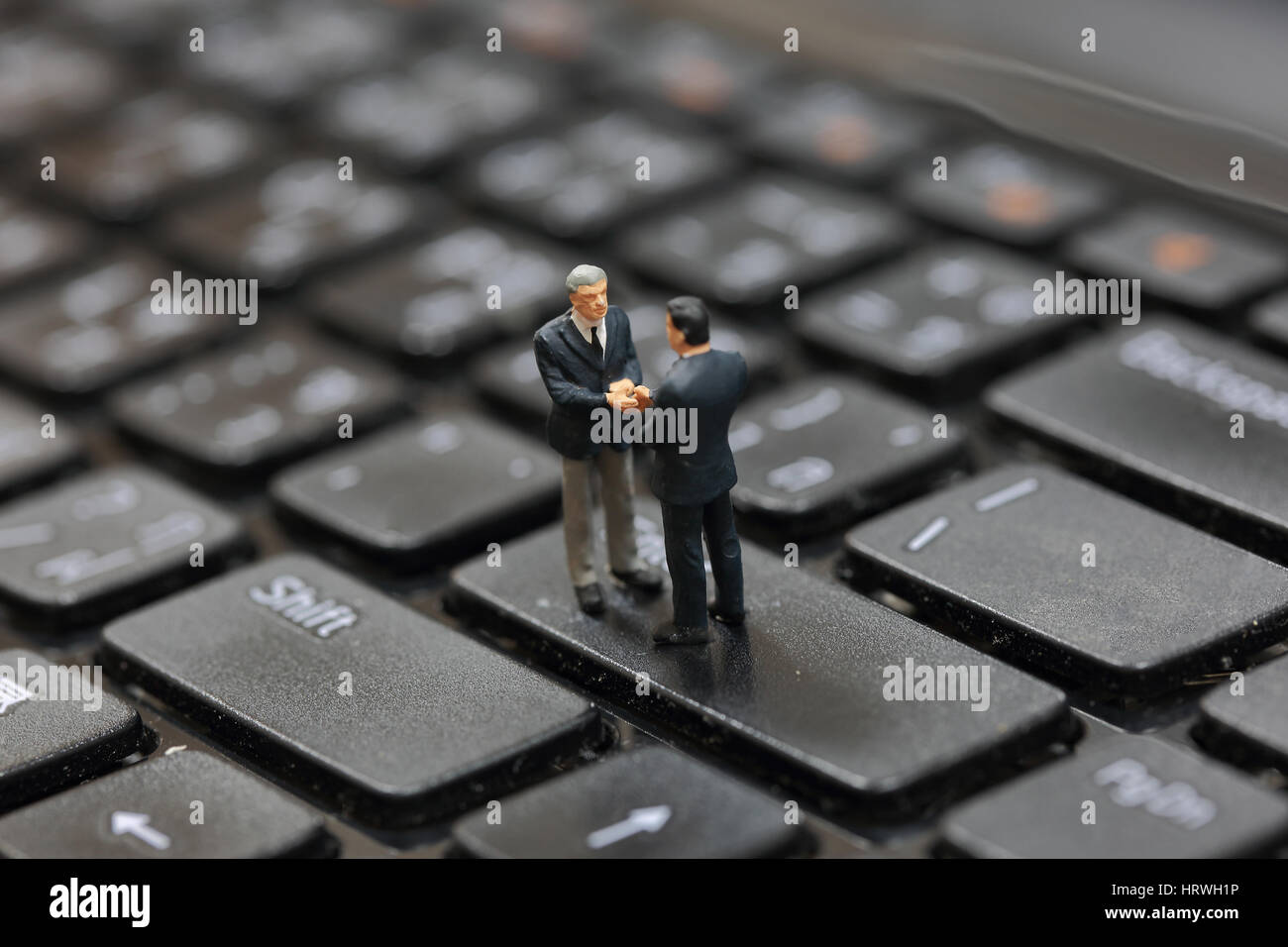 Selective focus of miniature business man handshake on the button Enter ...