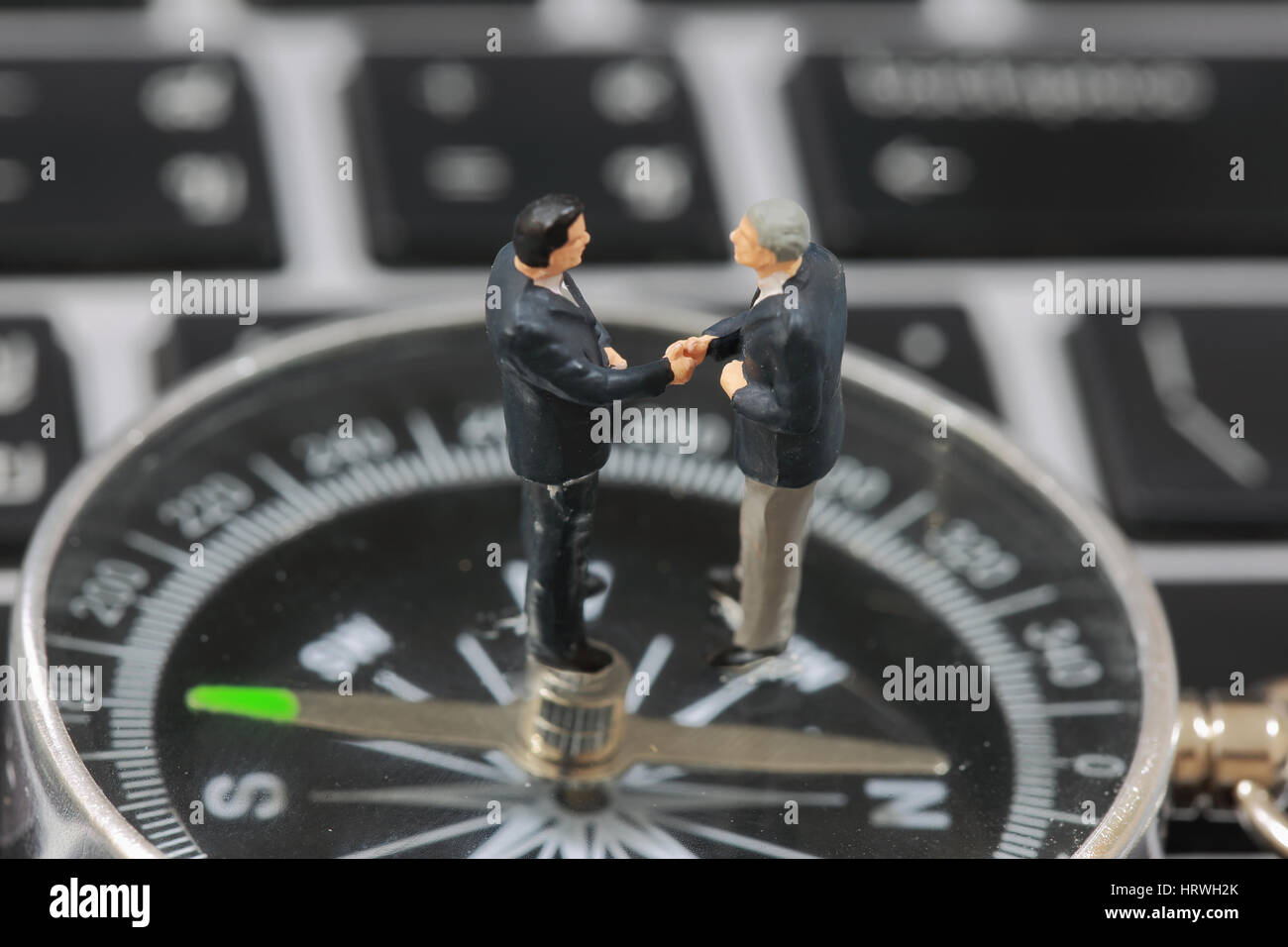 Selective focus of miniature businessman handshake on the compass ...