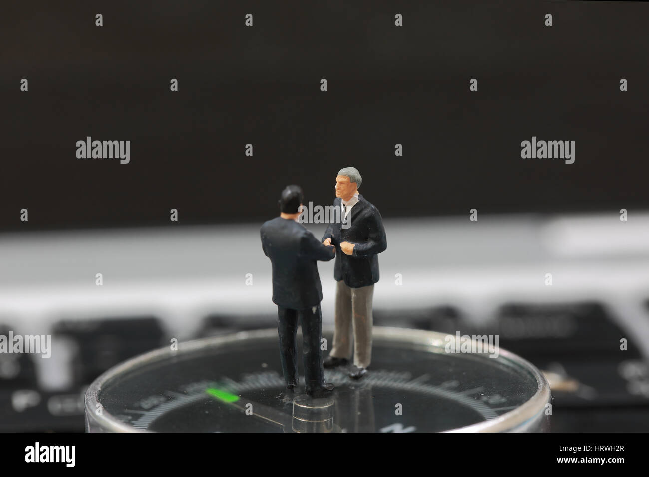 Selective focus of miniature businessman handshake stand up on the ...
