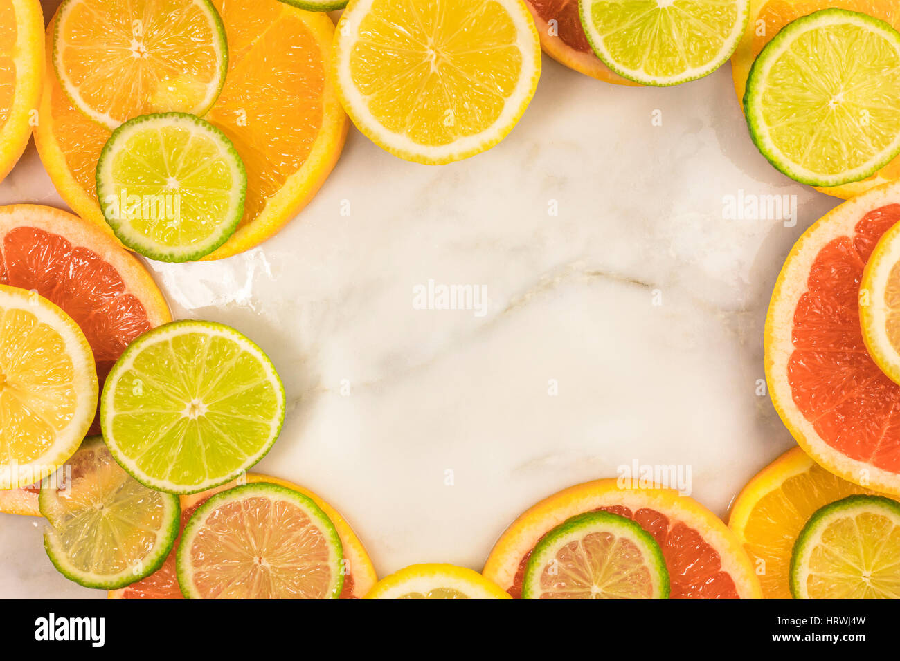 A vibrant frame made up of juicy citrus fruits, on a white marble ...