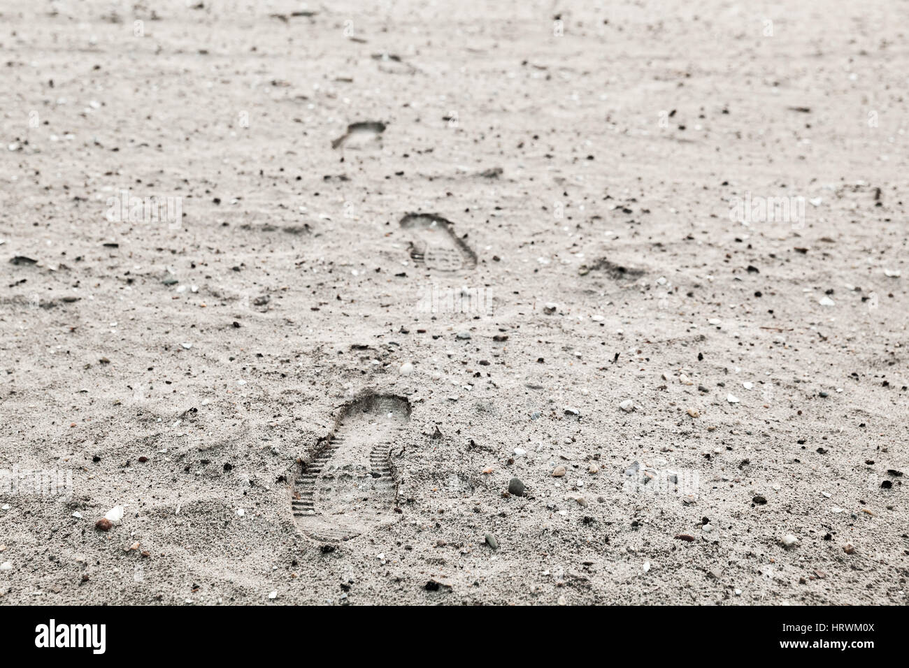 Human footprints in gray sandy ground, background photo with selective ...