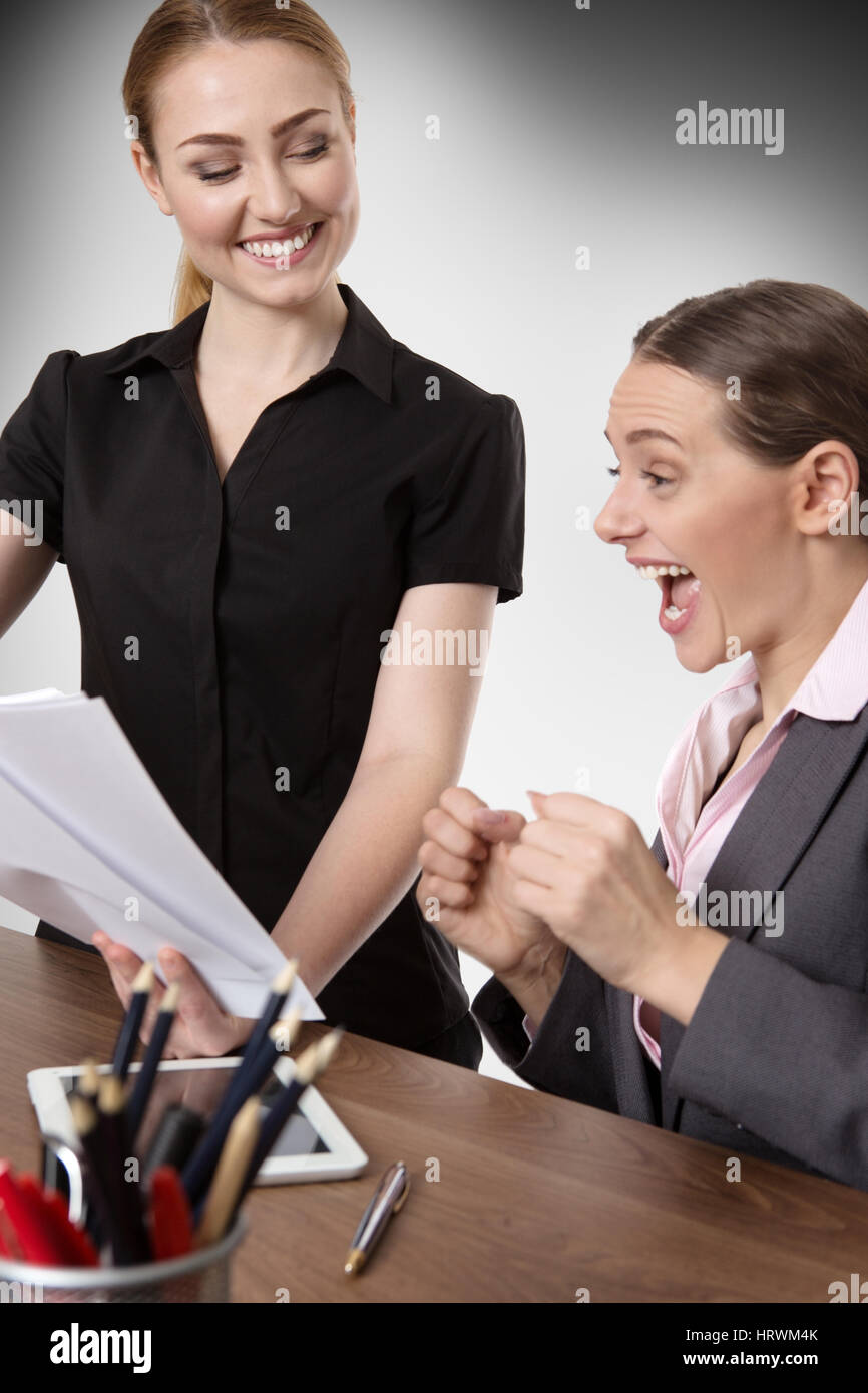 studio shot of two happy co-workers discussing some documents in the ...
