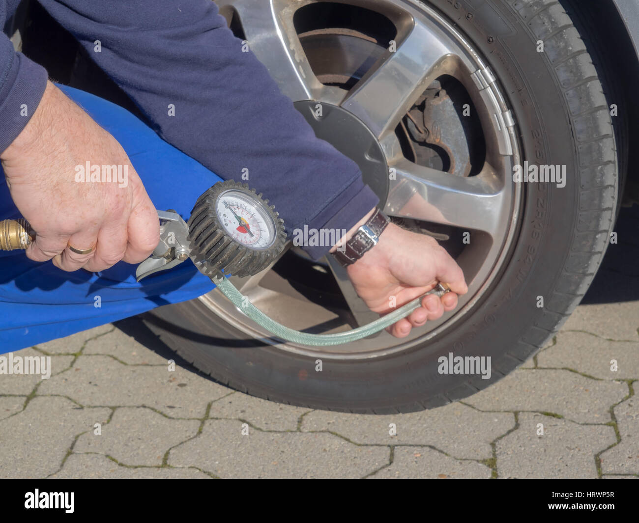 A man is measuring the air pressure of the tire of a car Stock Photo ...