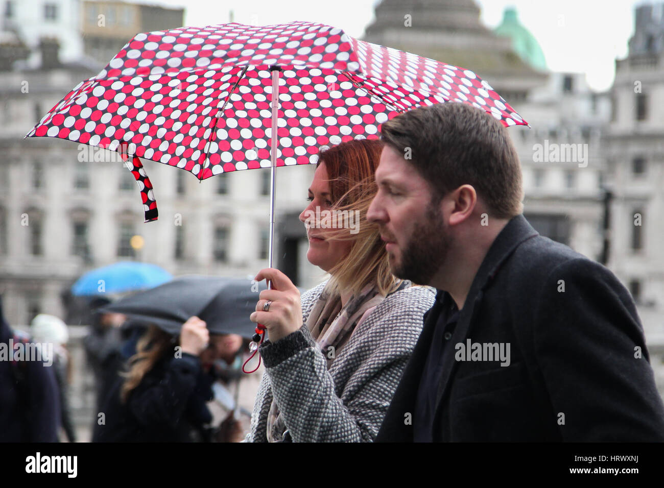 Trafalgar Square . London. UK 4 Mar 2017 - Tourists shelter under ...