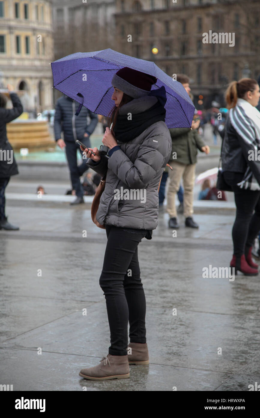 Trafalgar Square . London. UK 4 Mar 2017 - Tourists shelter under ...