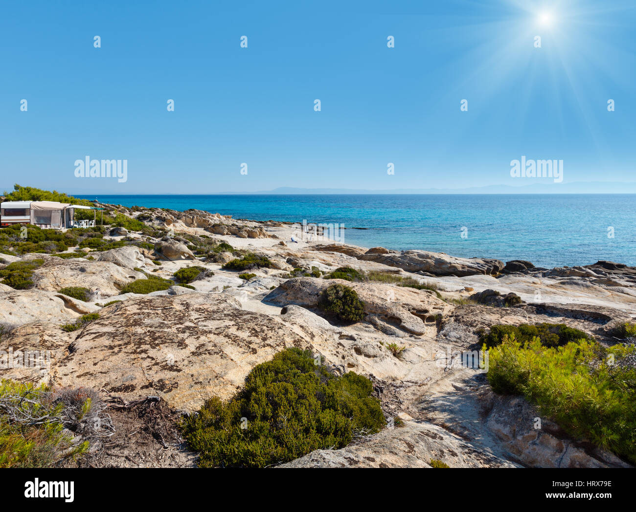 Sunshine above camping on rocky coast and small sandy beach near ...