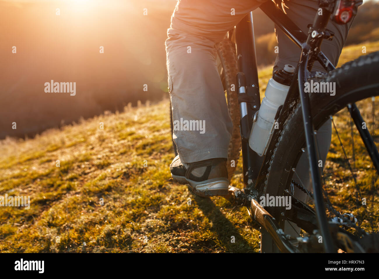 cyclist legs riding mountain bike on the hill in spring time. Close-up ...