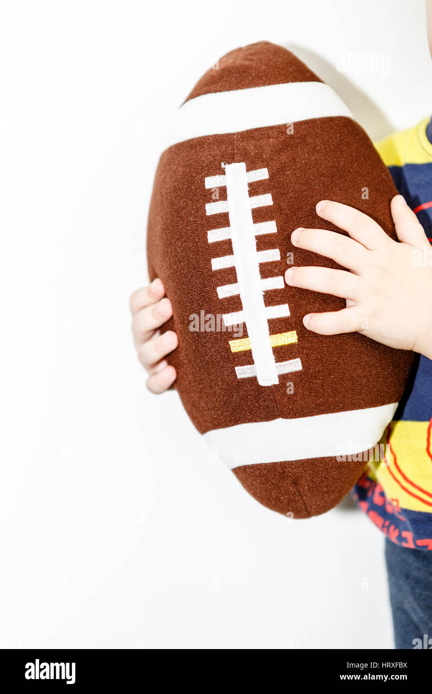 brown rugby ball toy for children in boys hands with white background ...