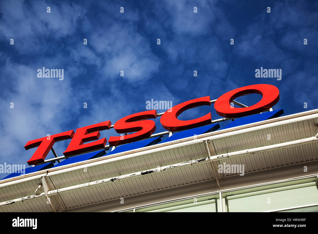 Bright Red Tesco Store Sign Set Against Mottled Blue and White Sky ...