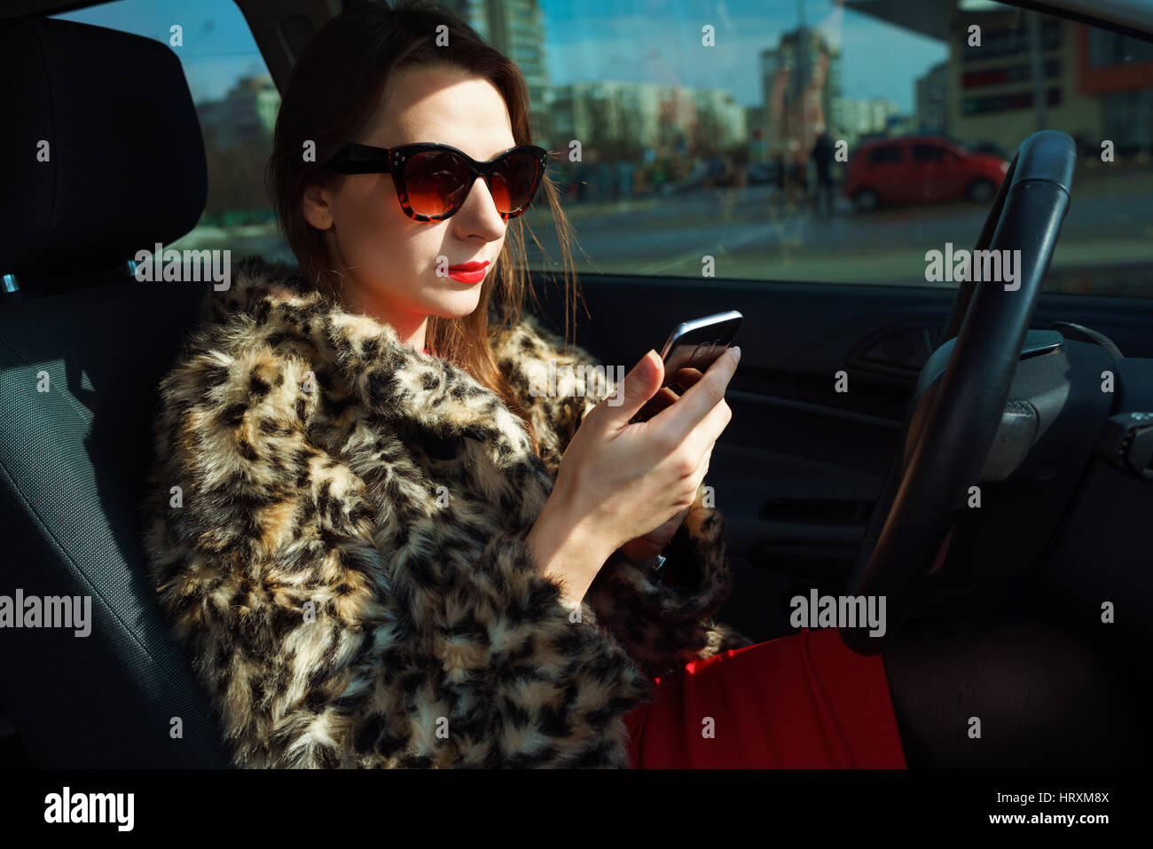 Beautiful woman in a fur coat with red lips using smartphone while ...