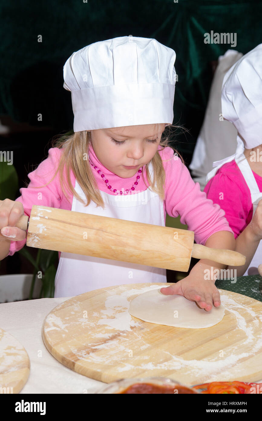little girl in chefs hat is cooking a pizza Stock Photo - Alamy