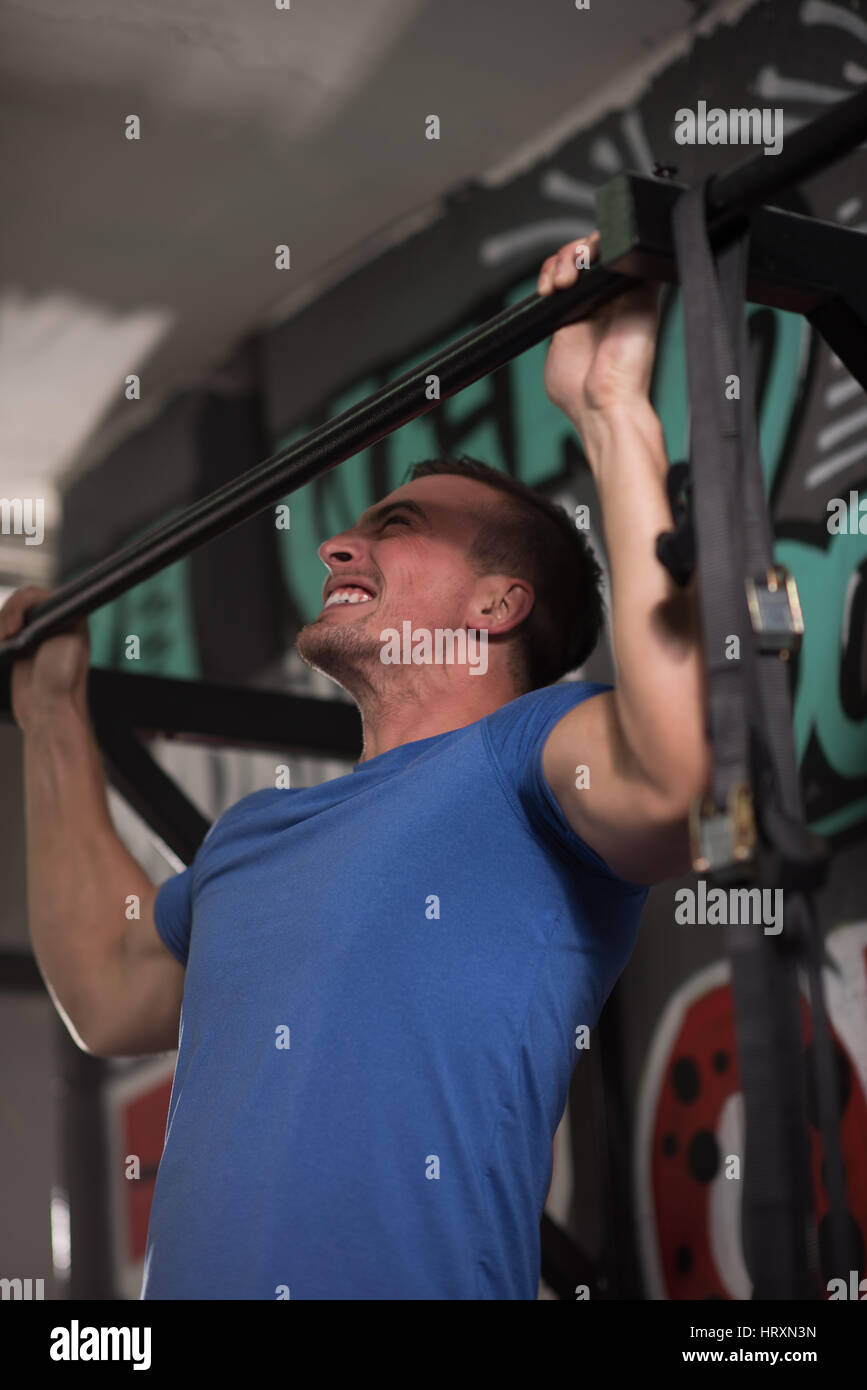 strong young man doing pull ups on a bar in a gym Stock Photo - Alamy