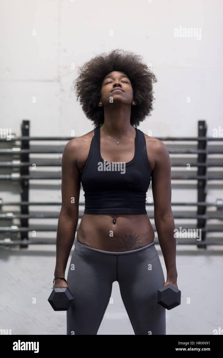 young beautiful African American woman doing bicep curls in a gym Stock ...