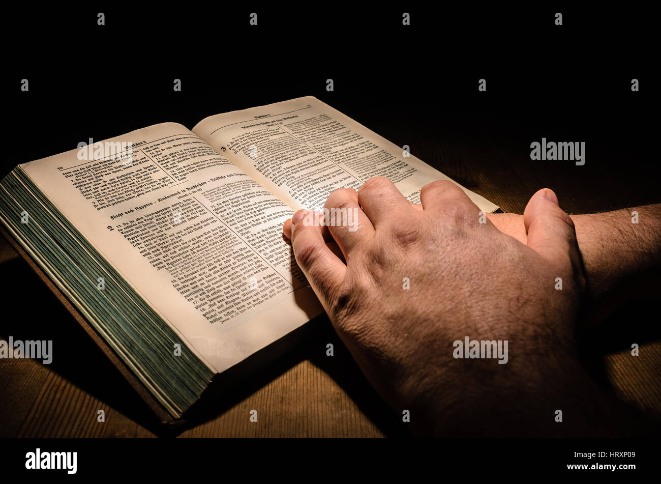 Hands placed on a bible, wooden table with dark background Stock Photo ...