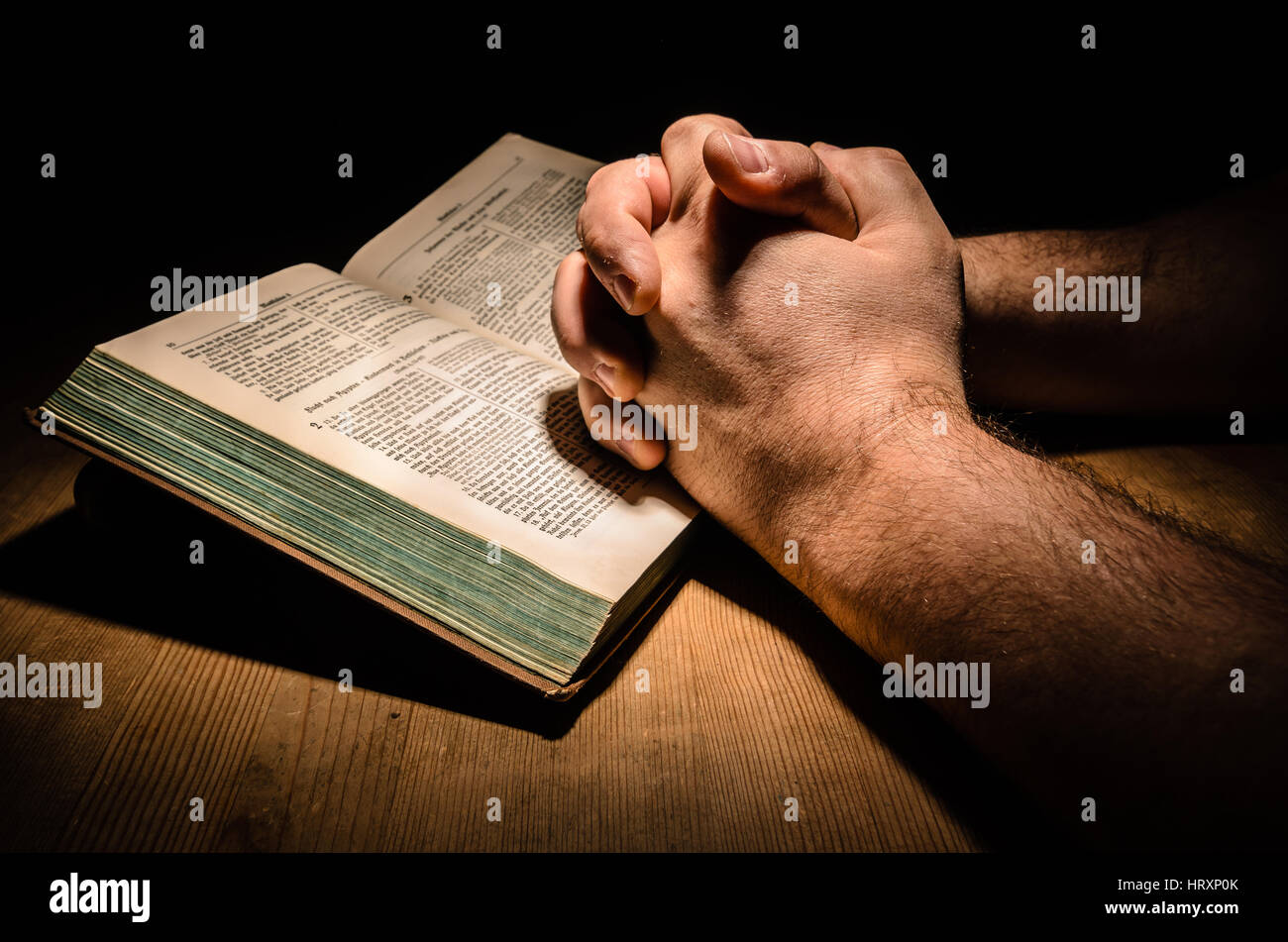 Hands placed on a bible, wooden table with dark background Stock Photo ...