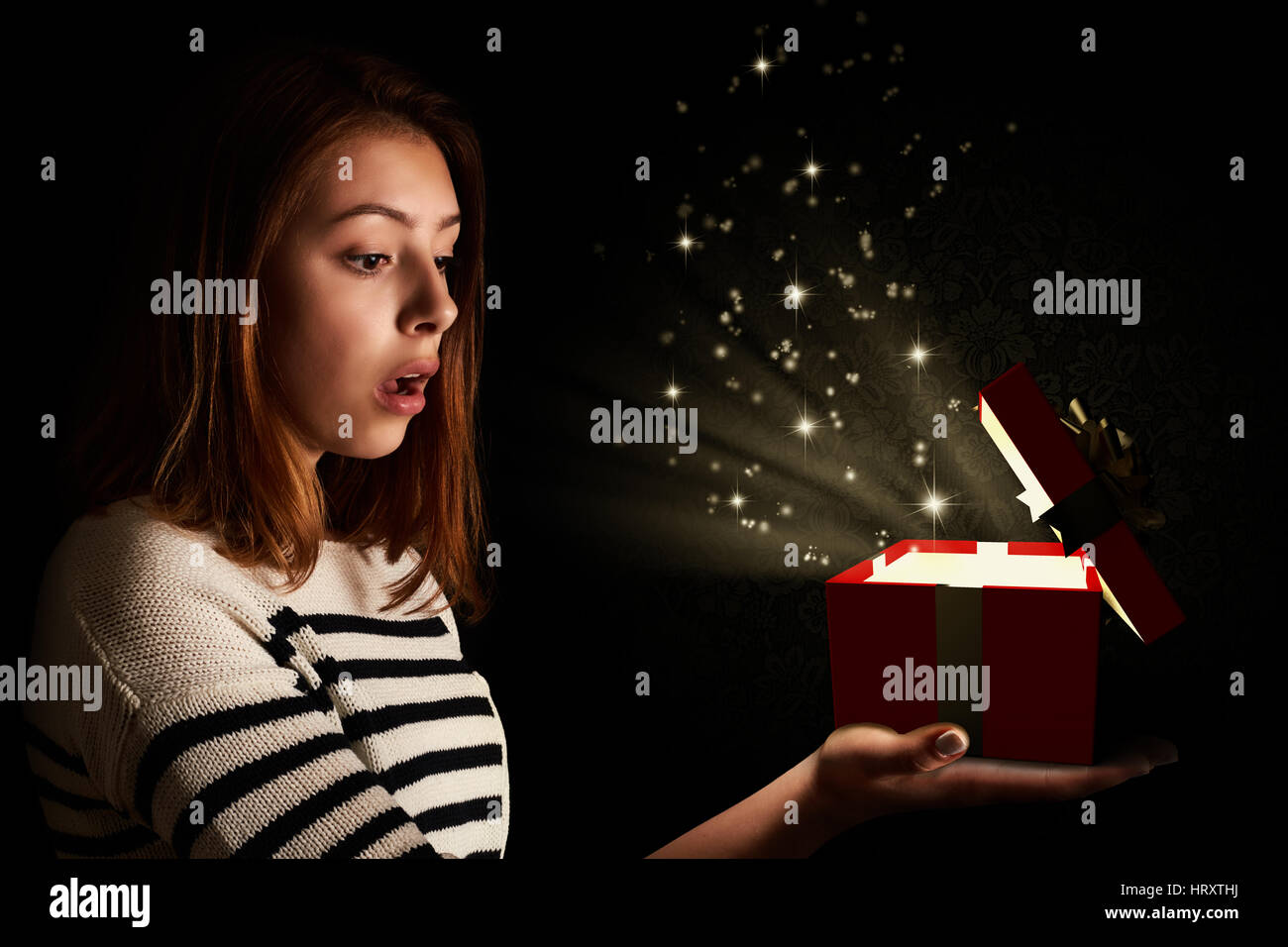Woman with open present, surprise sparkling stars on dark background ...