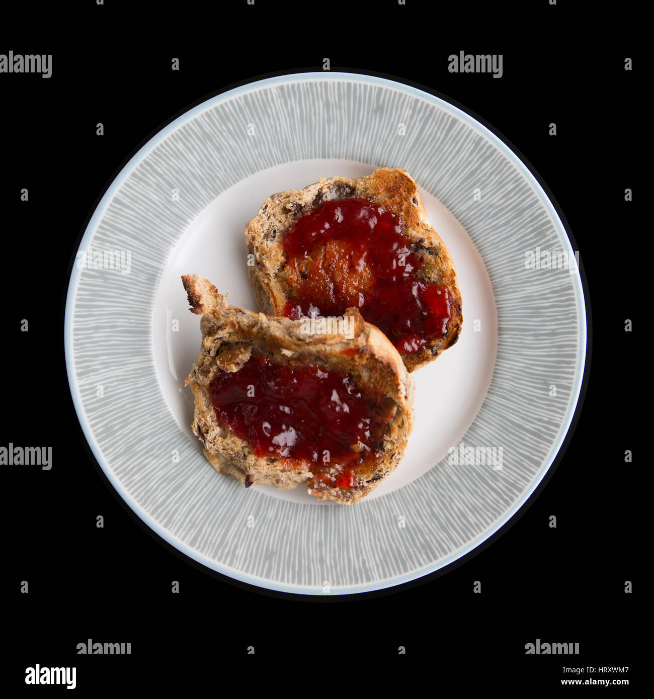 Plate with two hot toasted teacakes with jam on a black background ...