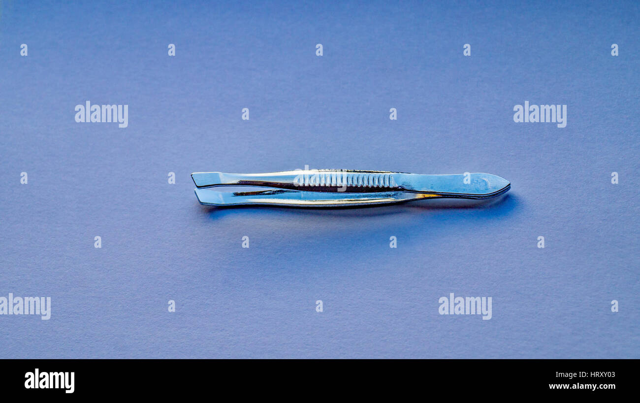 Tinted tweezers on a blue background Stock Photo - Alamy