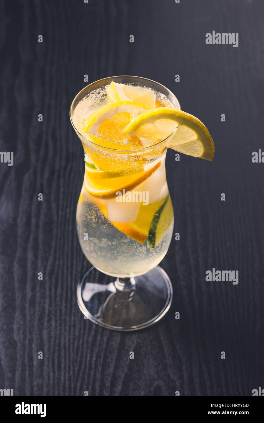 Fresh alcoholic drink with citrus fruits on dark wooden background ...