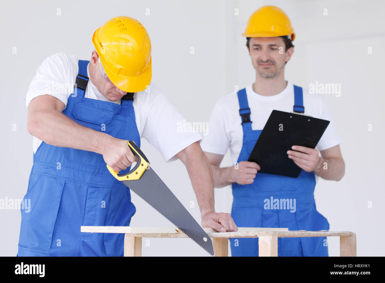 Two workmen in protective workwear with saw and folder Stock Photo - Alamy