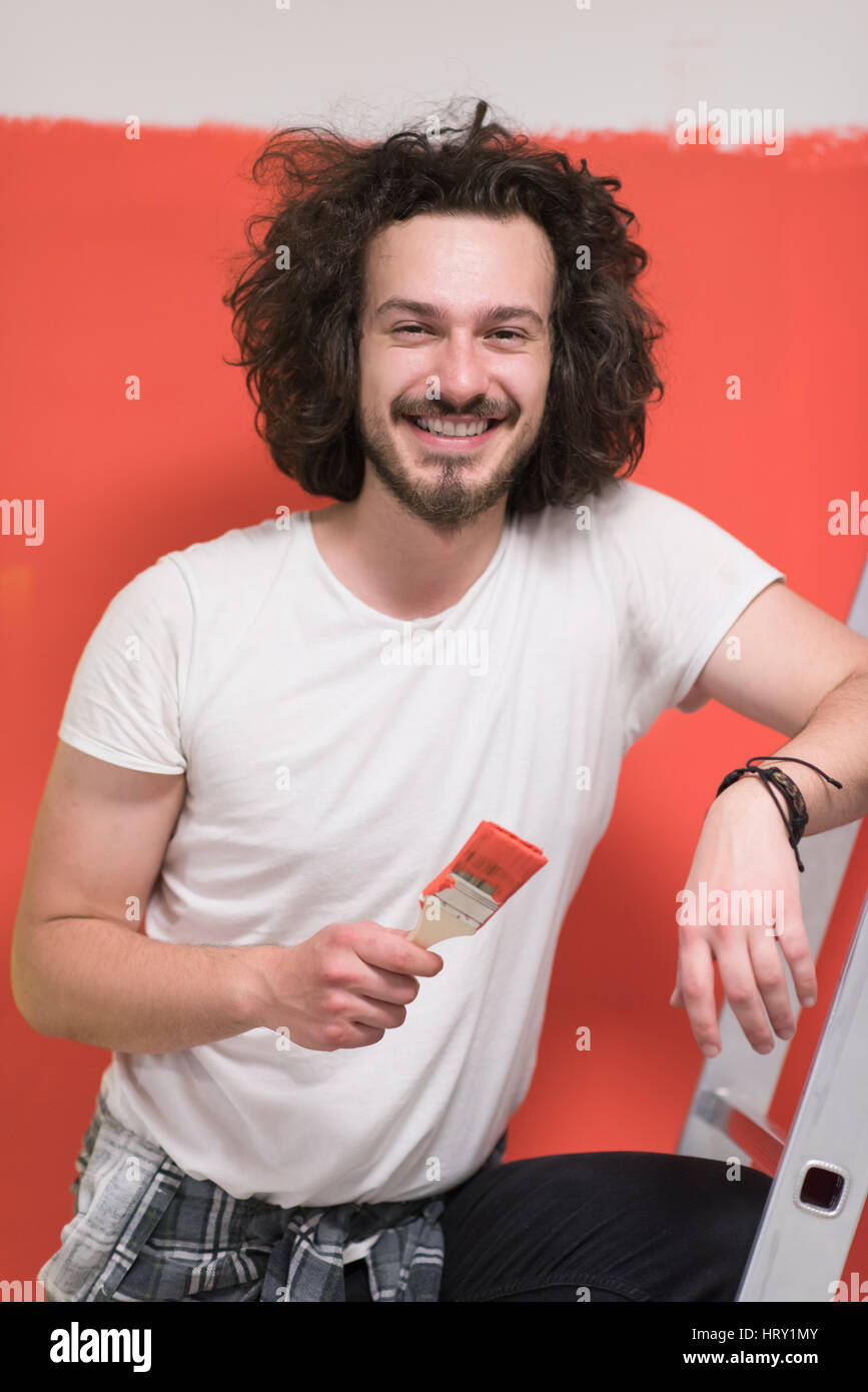 Portrait of a beautiful young man with funny hair and brush over color ...