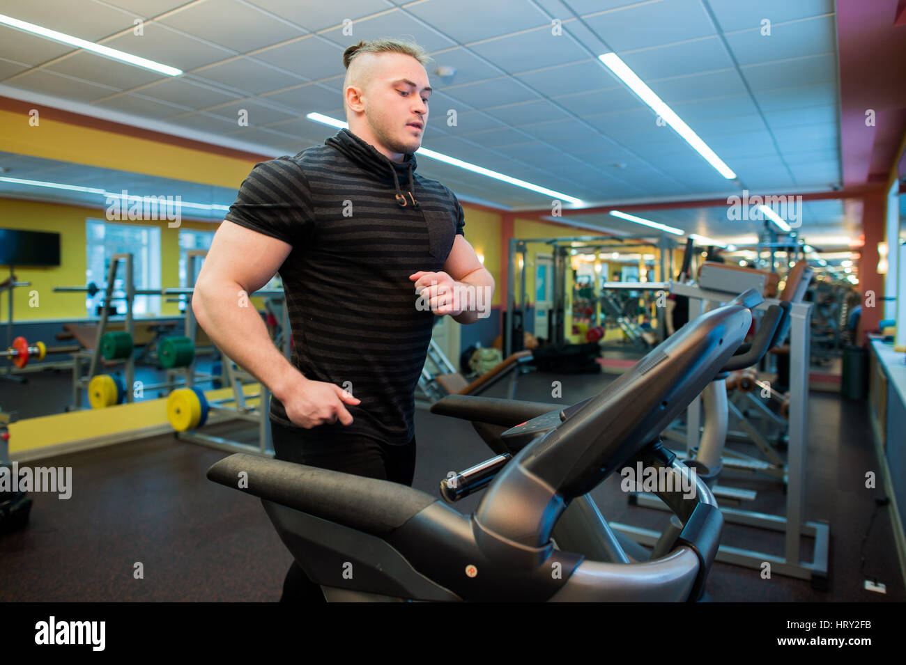 Attractive young muscular man while running on a treadmill in gym Stock ...
