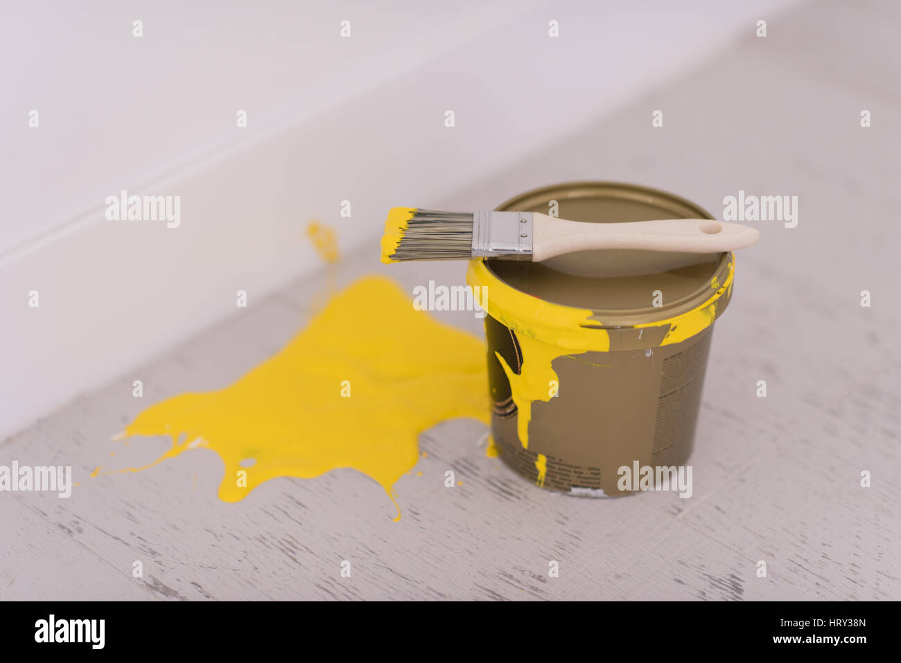 Yellow paint tin can with brush on top with yellow strokes on the ...