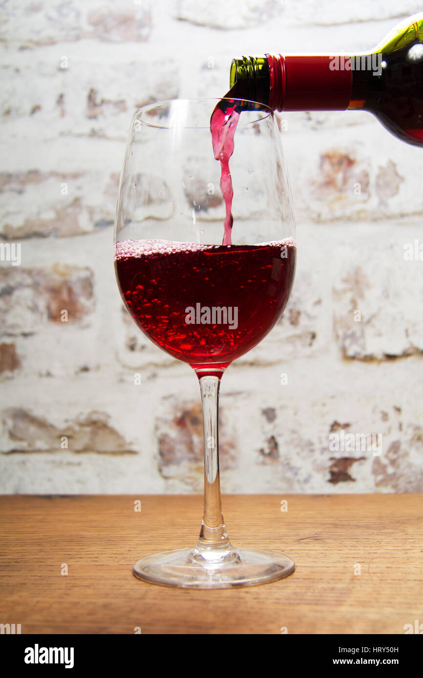 Glass of full bodied red wine being poured from bottle Stock Photo - Alamy