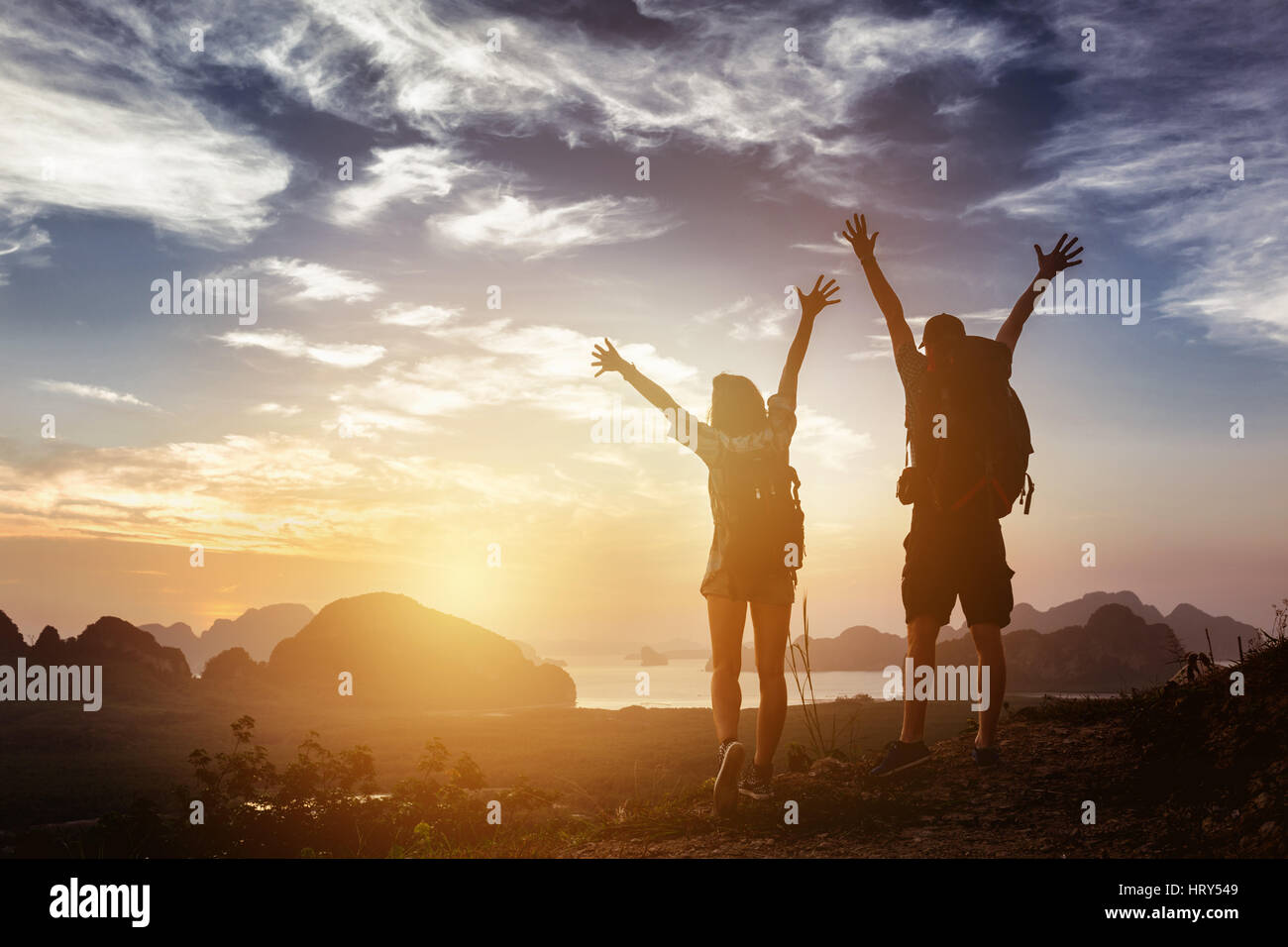 Happy couple stands in winner pose with rised arms on background of ...