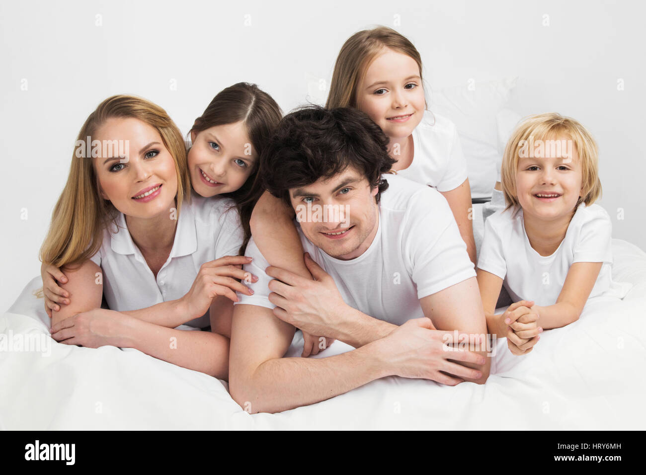 Smiling family with three children wake up in bed Stock Photo - Alamy