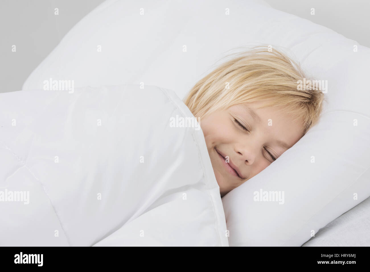 Cheerful smiling blond boy sleep in white bed Stock Photo - Alamy