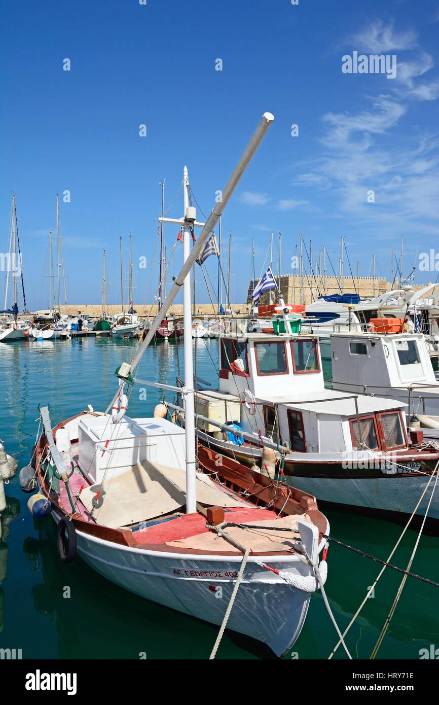 Traditional fishing boats moored in the harbour with Koules castle to ...