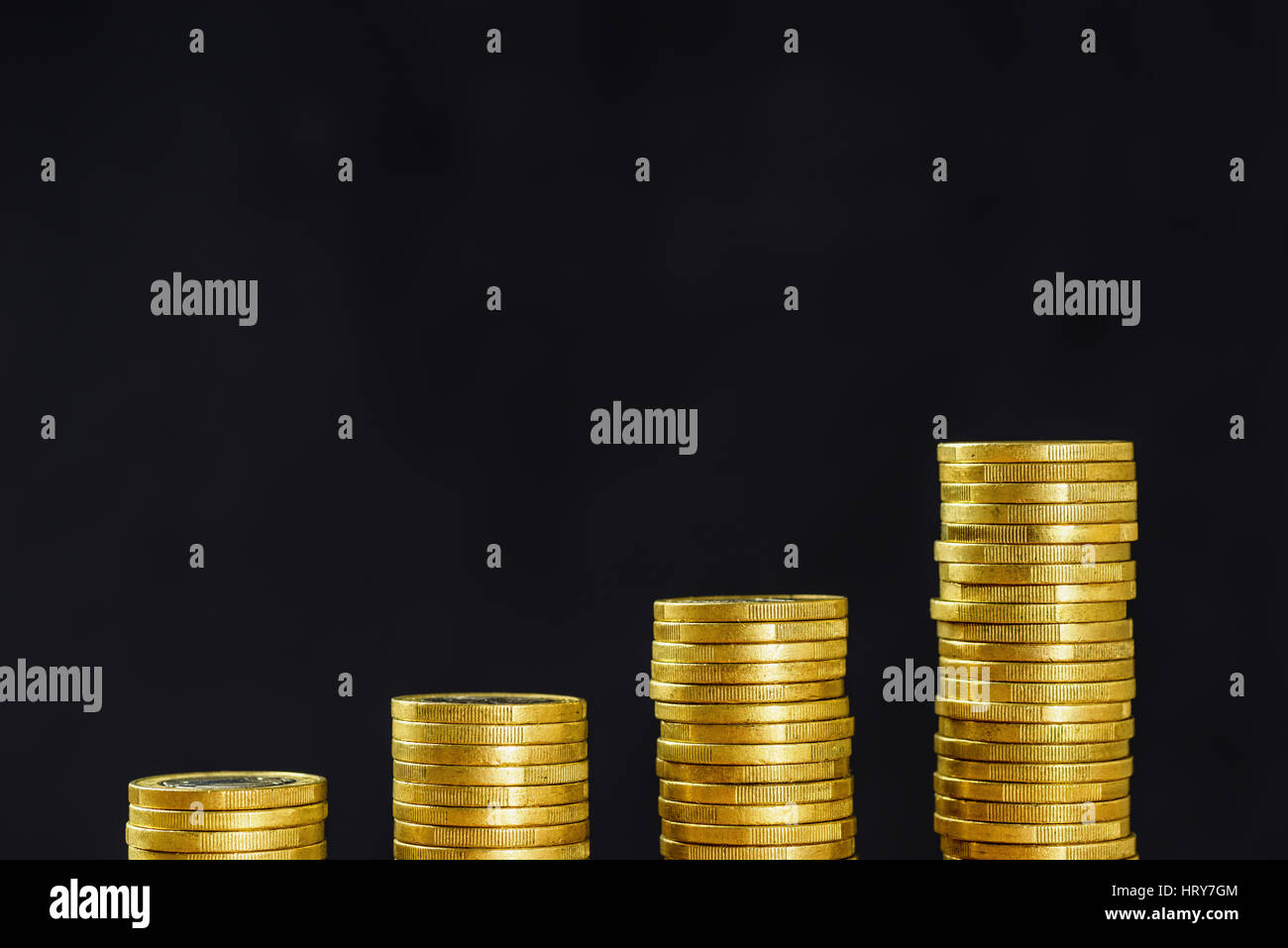 Golden coin stacks on a black background Stock Photo - Alamy