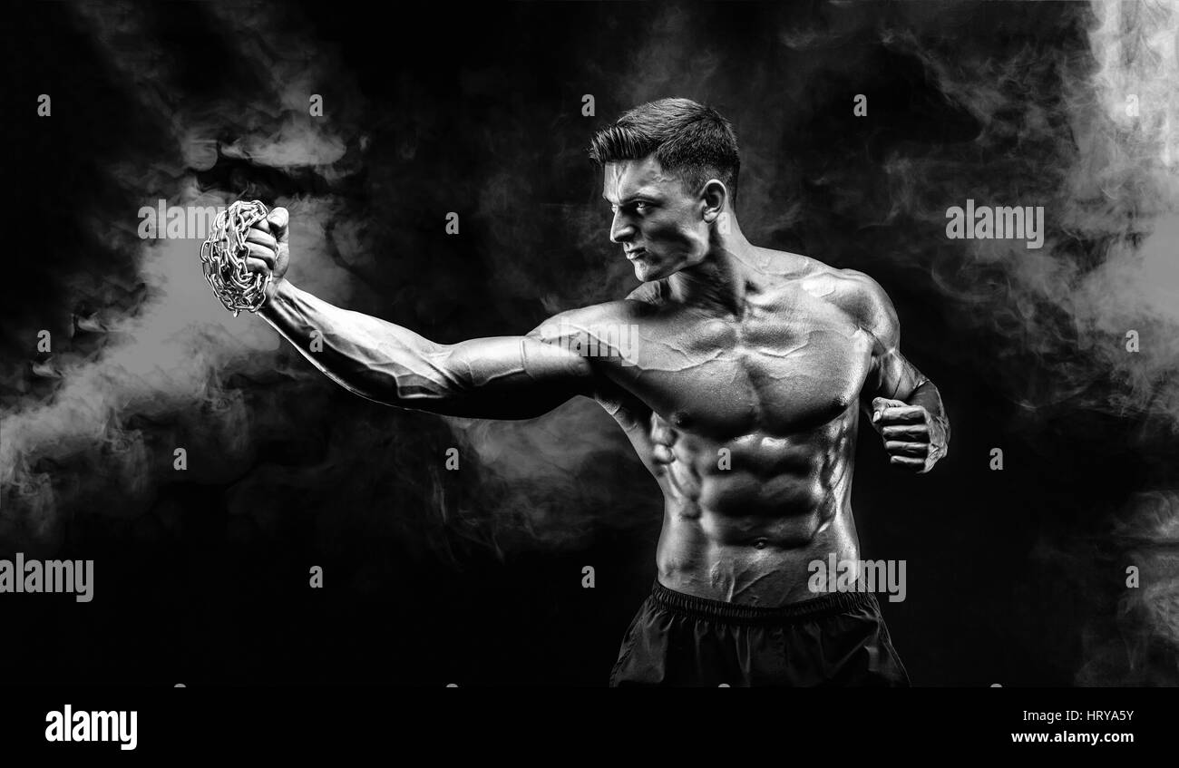 Serious muscular fighter doing the punch with the chains braided over ...