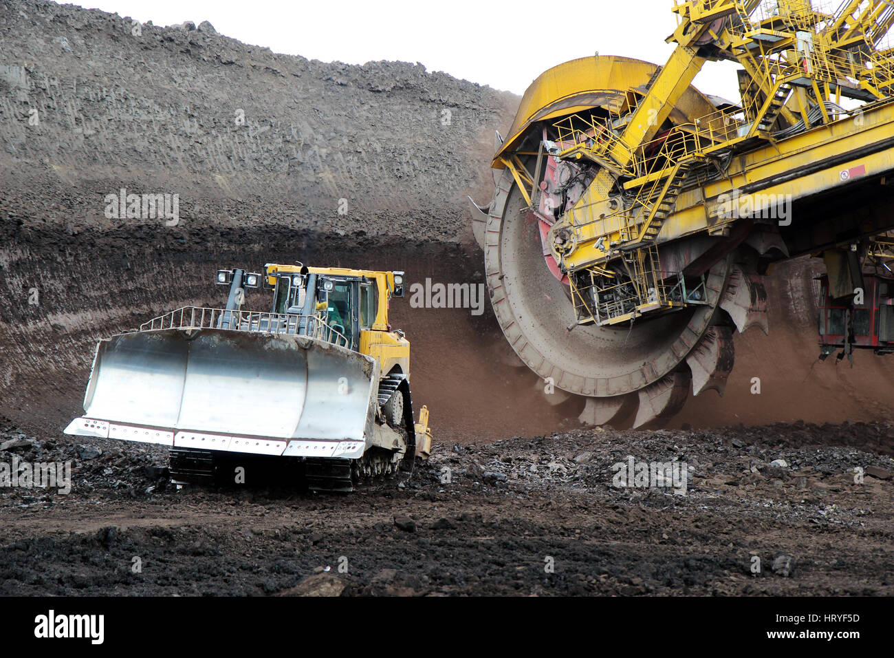 bulldozer and huge mining excavator wheel in brown coal mine Stock ...