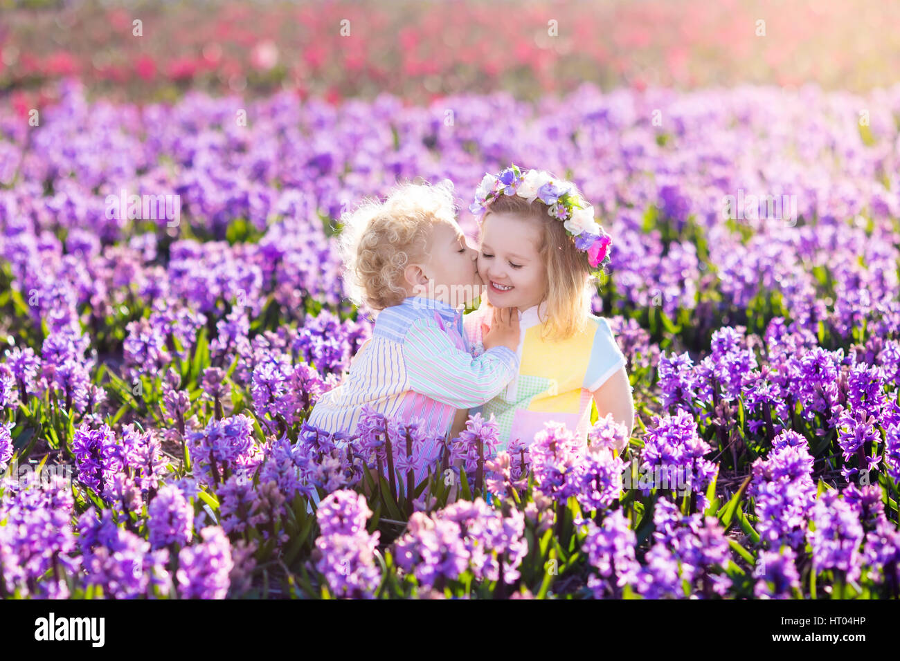 Kids gardening. Children play outdoors in hyacinths meadow. Little girl ...