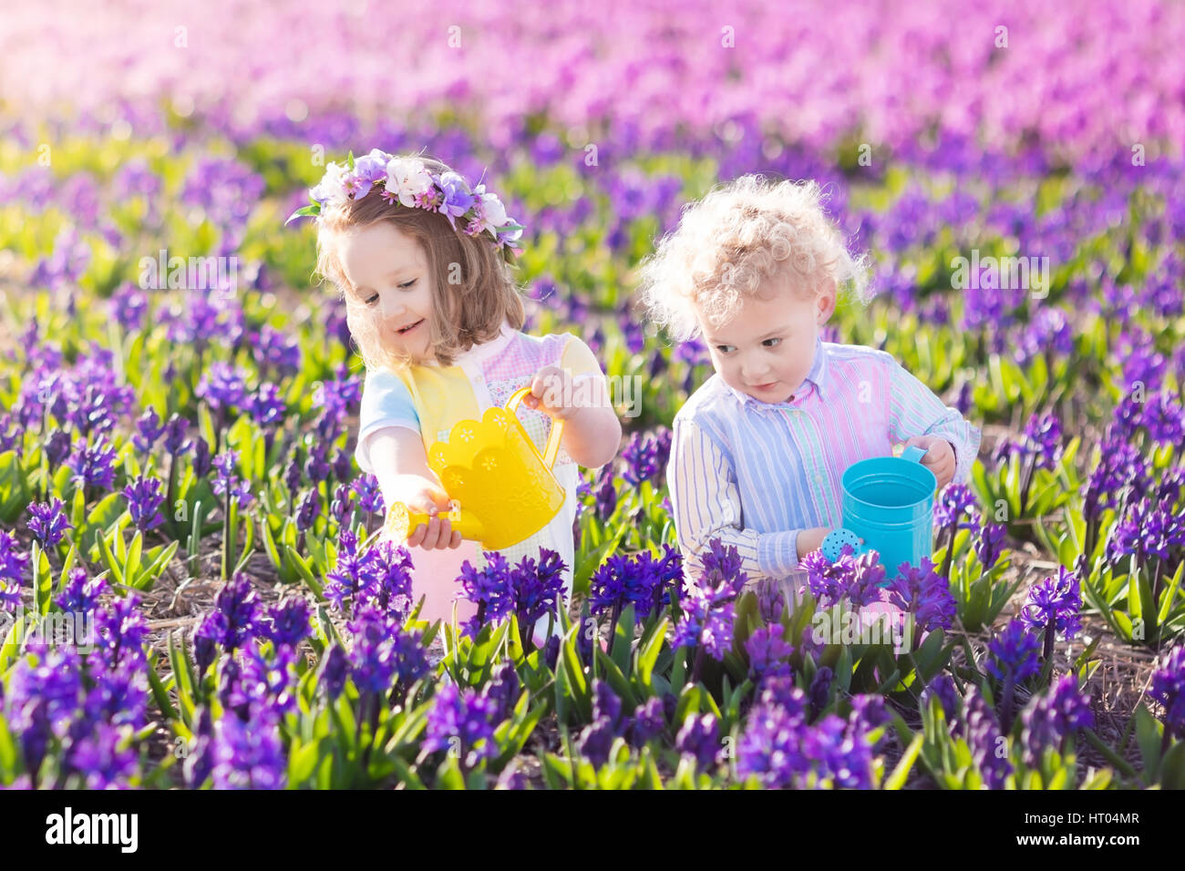 Children planting spring flowers in sunny garden. Little boy and girl ...