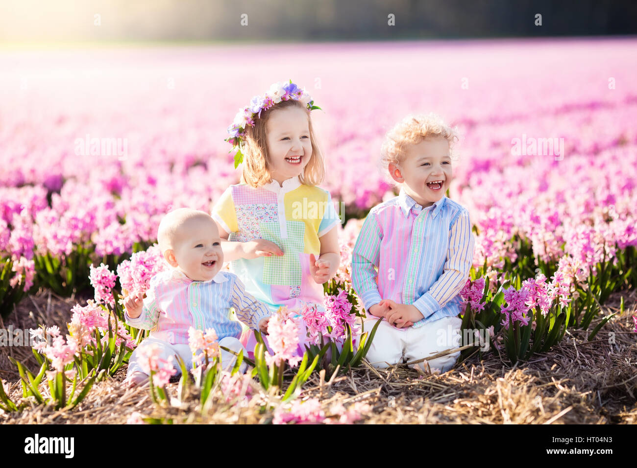 Three children playing in beautiful hyacinth flower field. Little girl ...