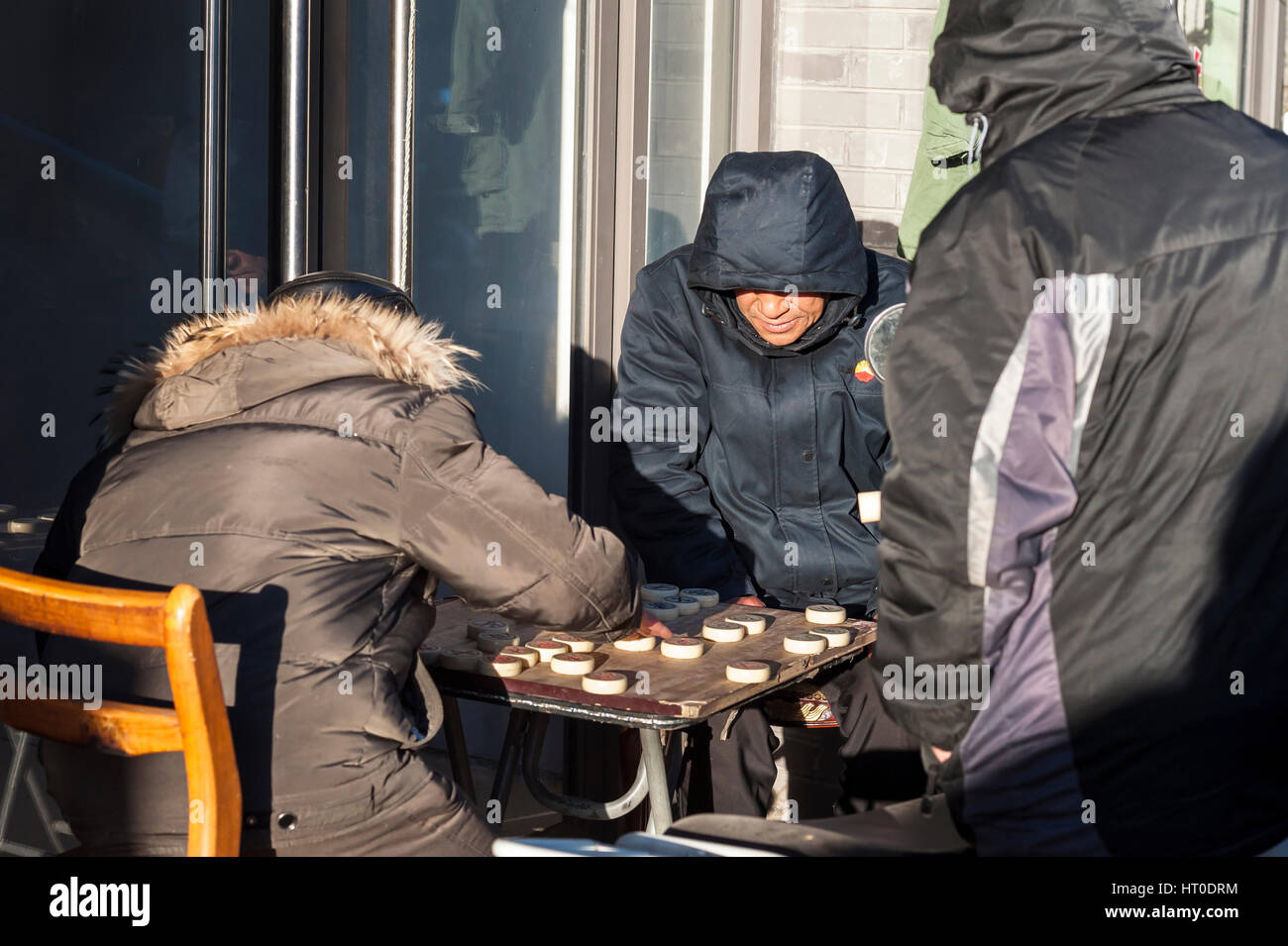 BEIJING, CHINA - DEC 2013 - Three men play the ancient Chinese game of ...