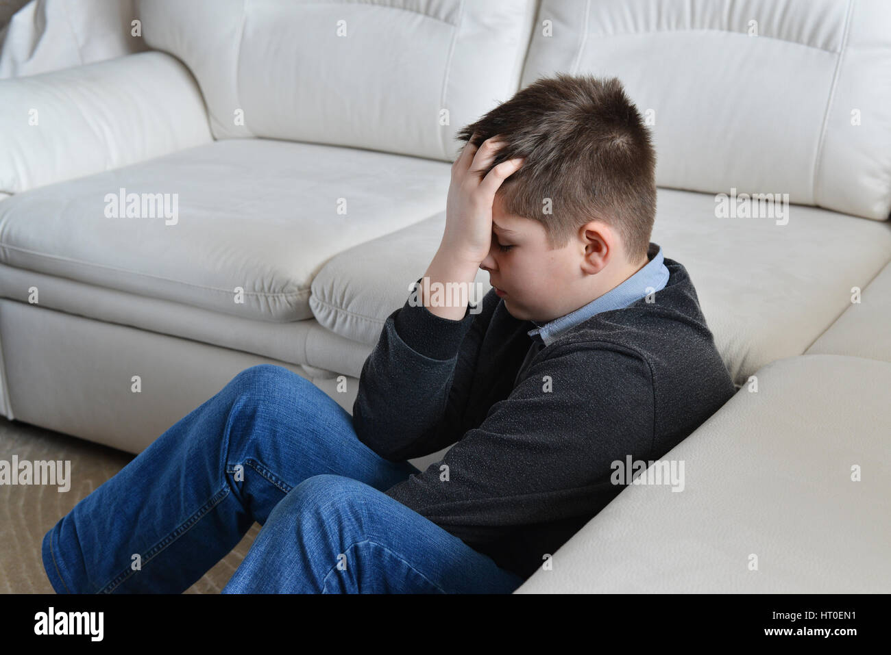 Upset teenager 13 years sitting near couch and holding his head in ...