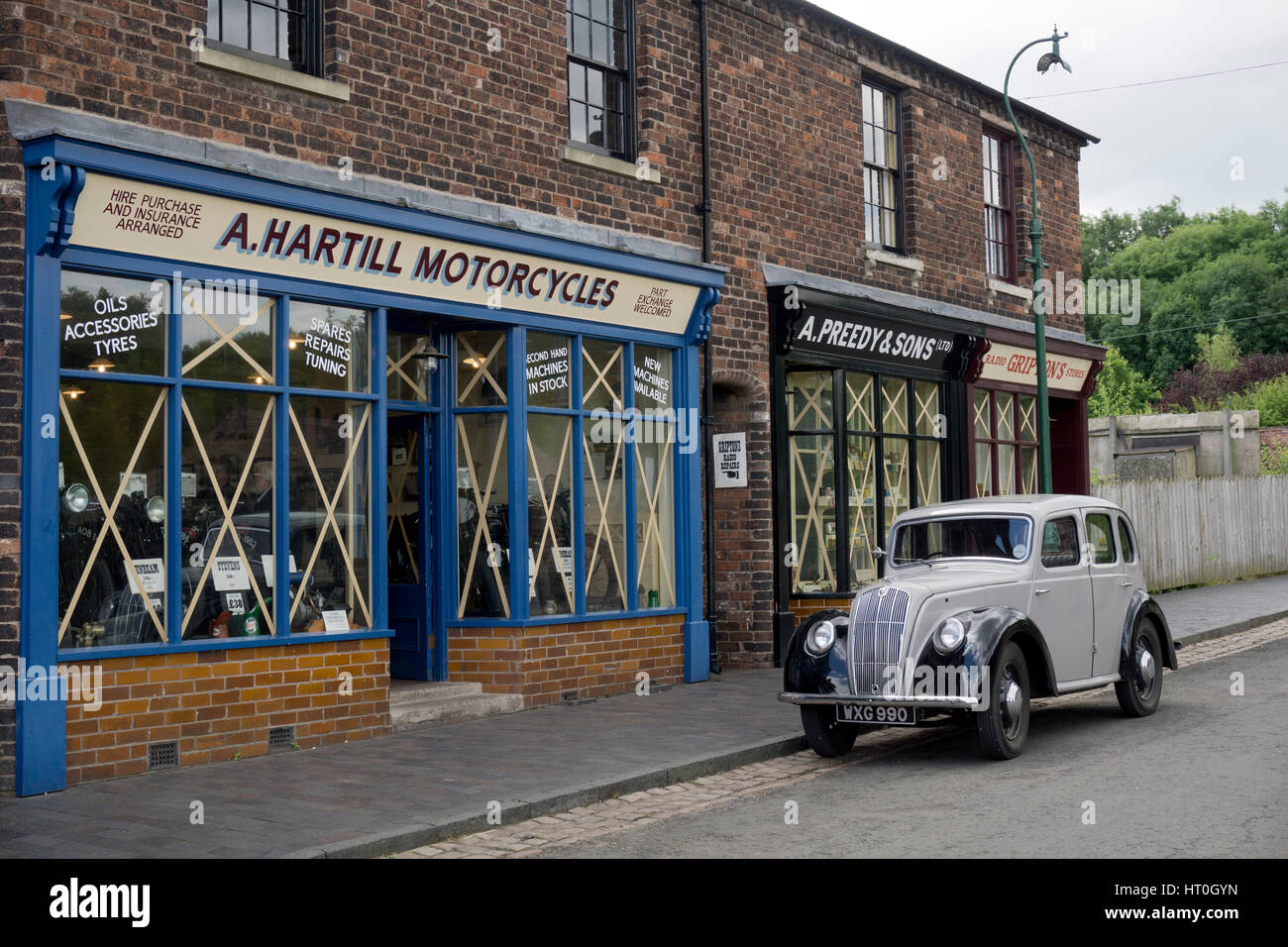 Classic car parked on a street outside shops with taped windows. A ...