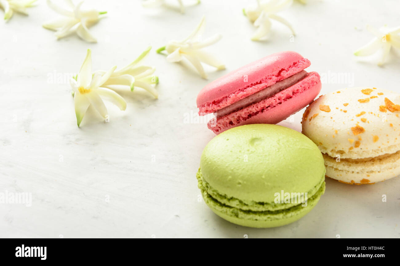 Varicolored macaroons and flowers on a white background in light key ...