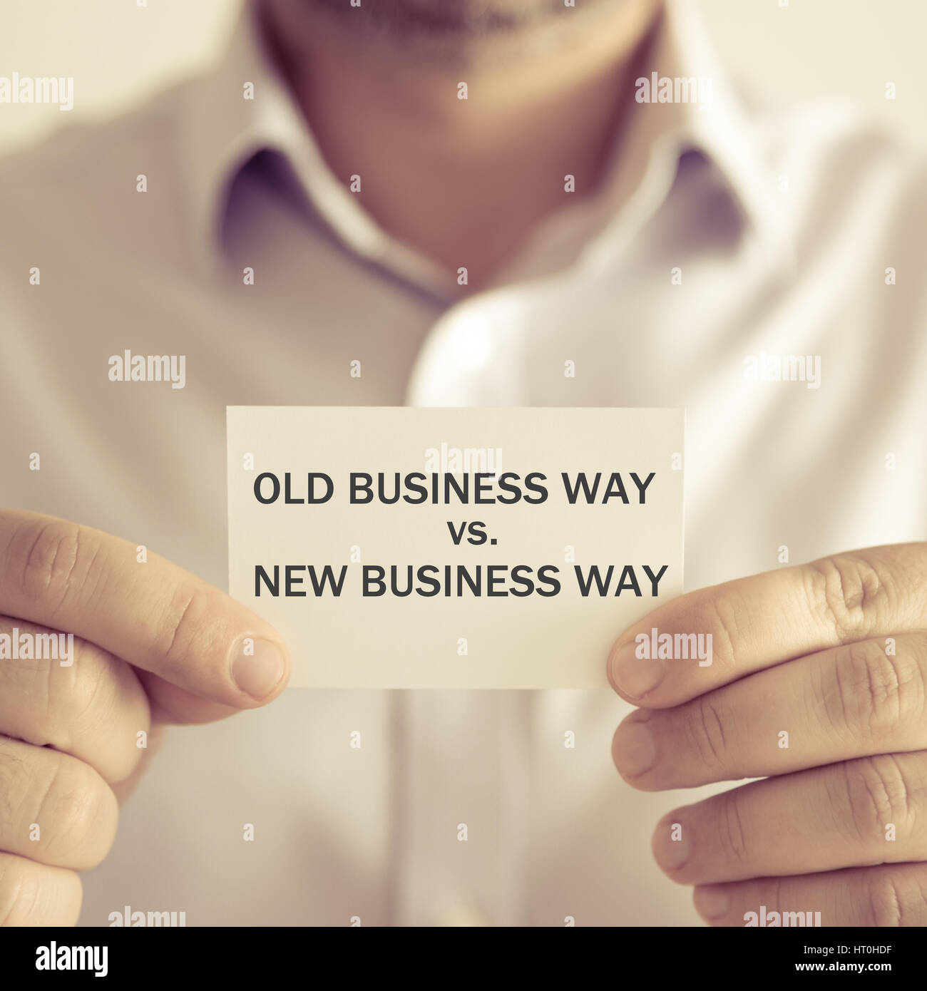 Closeup on businessman holding a card with text OLD BUSINESS WAY VERSUS ...