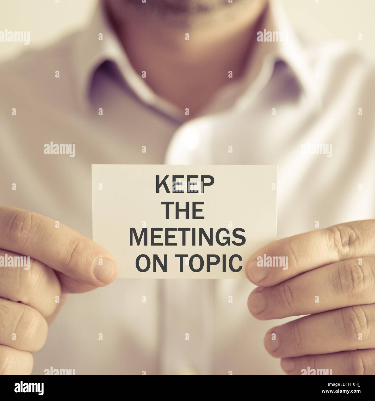 Closeup on businessman holding a card with text KEEP THE MEETINGS ON ...