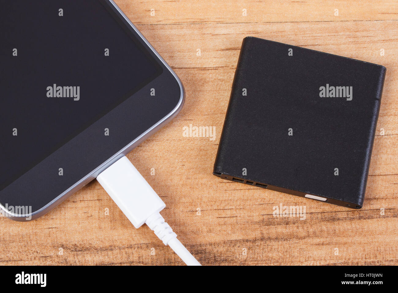 Mobile phone, plug of charger and telephone battery on table ...