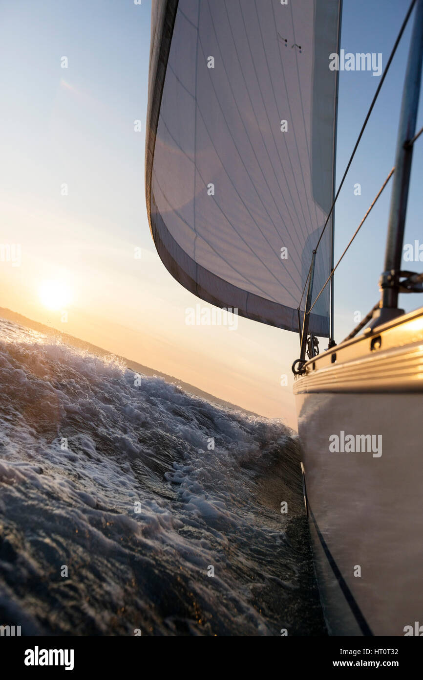 Yacht sailing in rough sea during sunset Stock Photo - Alamy