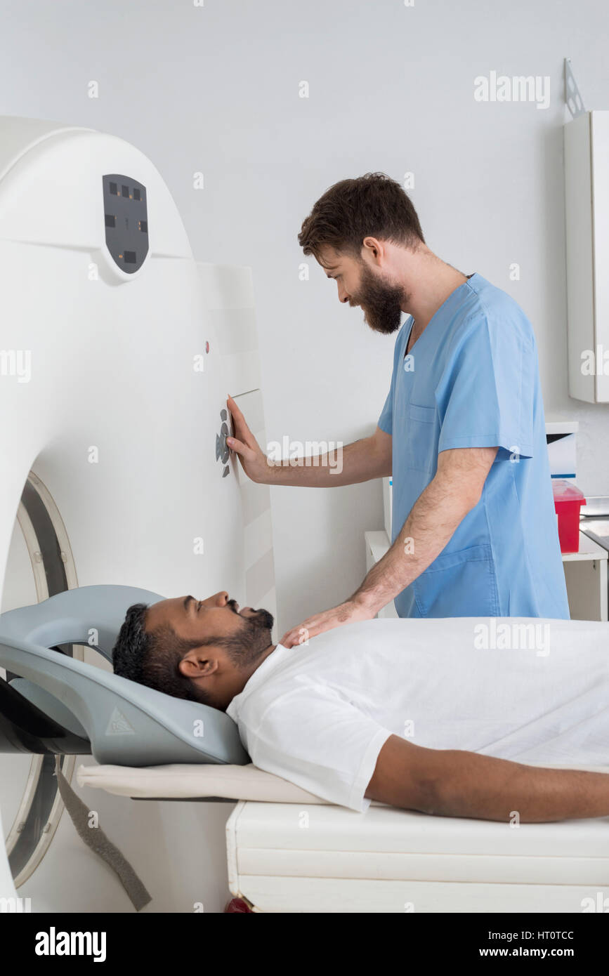 Young male doctor about to start CT scan on patient in examination room ...