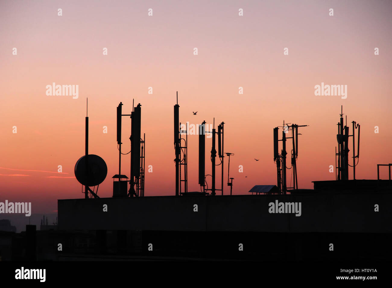 silhouette of GSM transmitters on the roof office building at dusk ...